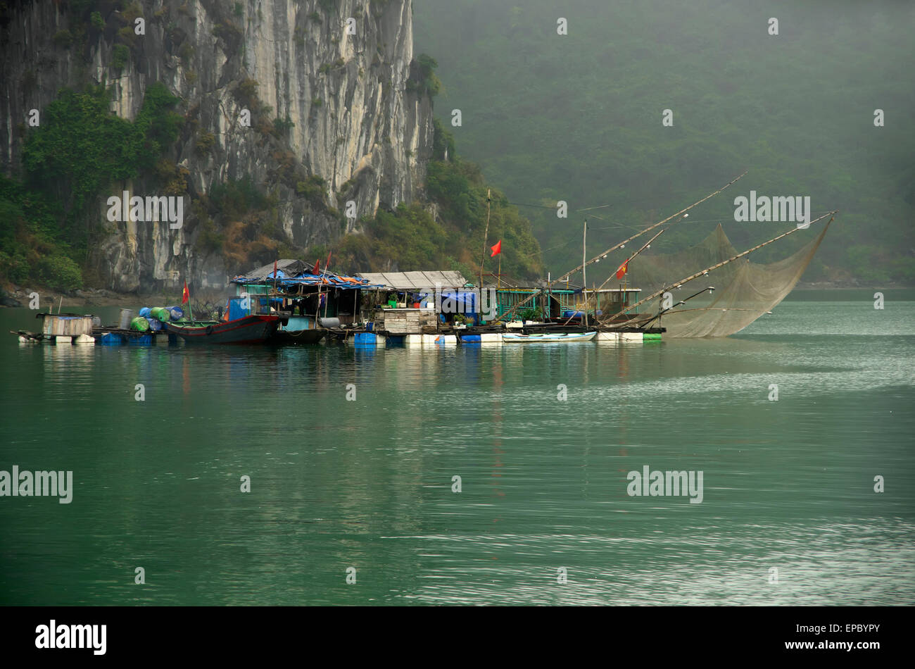 Floating houses and boats, with fishnets extended on poles over water ...