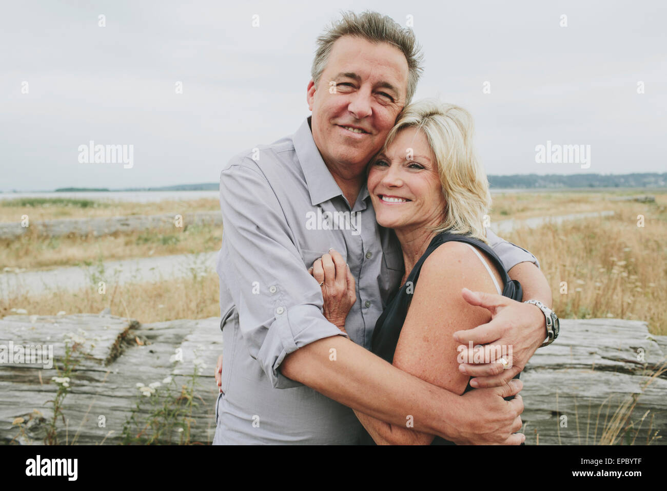 Happy senior couple embracing on a grassy beach; Coquitlam, British ...