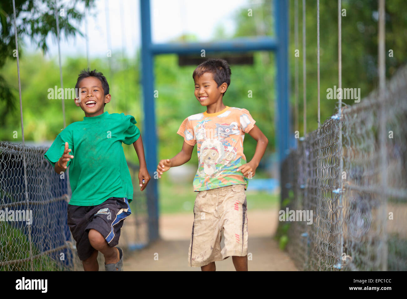 Boys running on a bridge; Battambang, Cambodia Stock Photo - Alamy