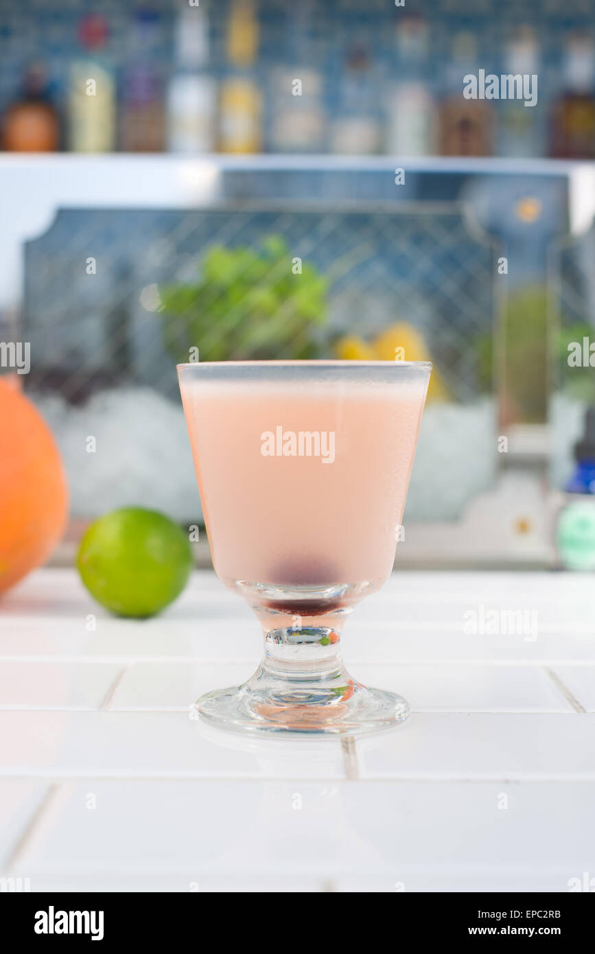 A pink, rum-based cocktail with a colorful bar background Stock Photo ...