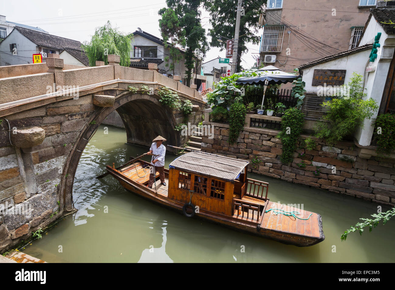 Man punting a boat by a bridge over the North-South canal by Pingjiang ...