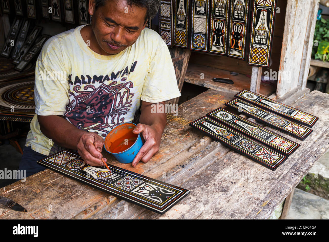 Man painting a traditional Toraja design on piece of wood, Kete Kesu ...