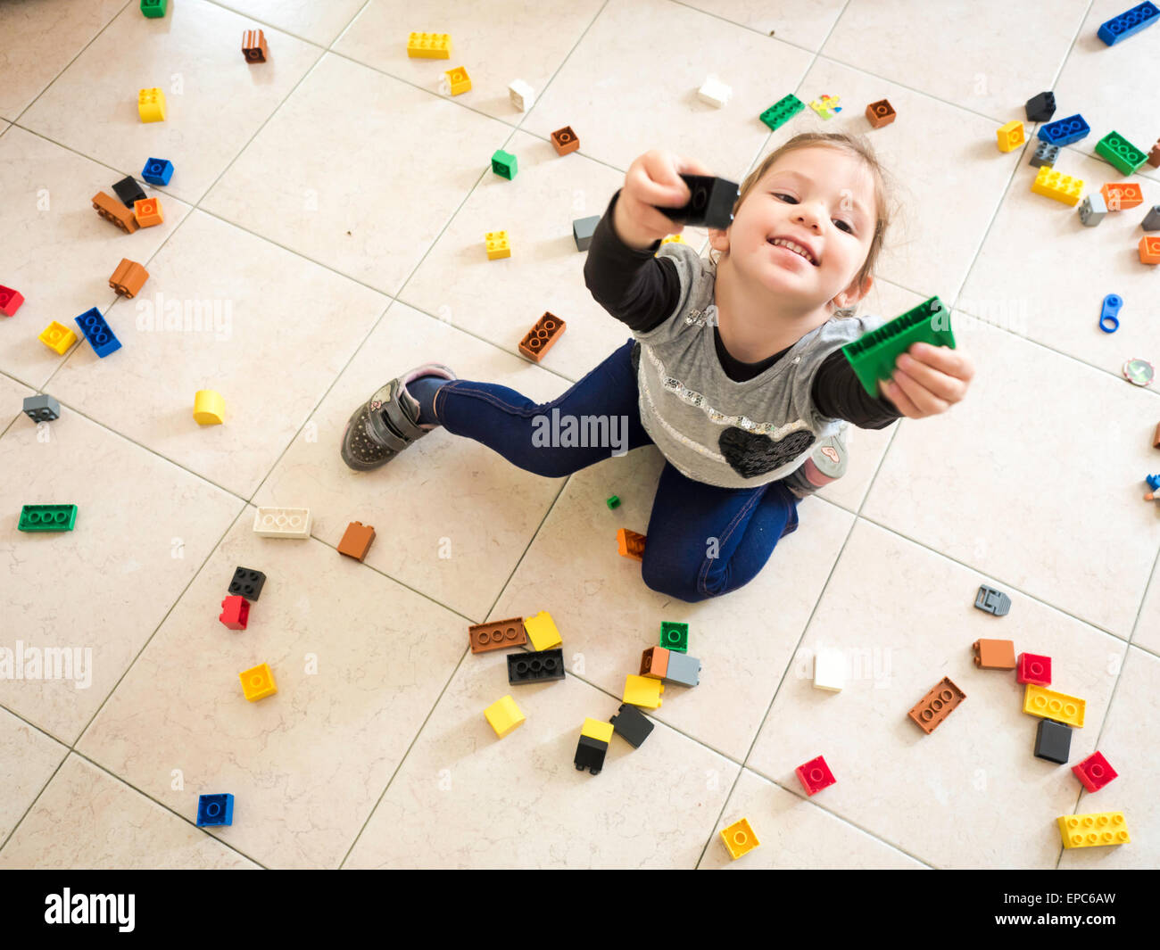 girl playing with colored bricks scattered on the floor Stock Photo - Alamy