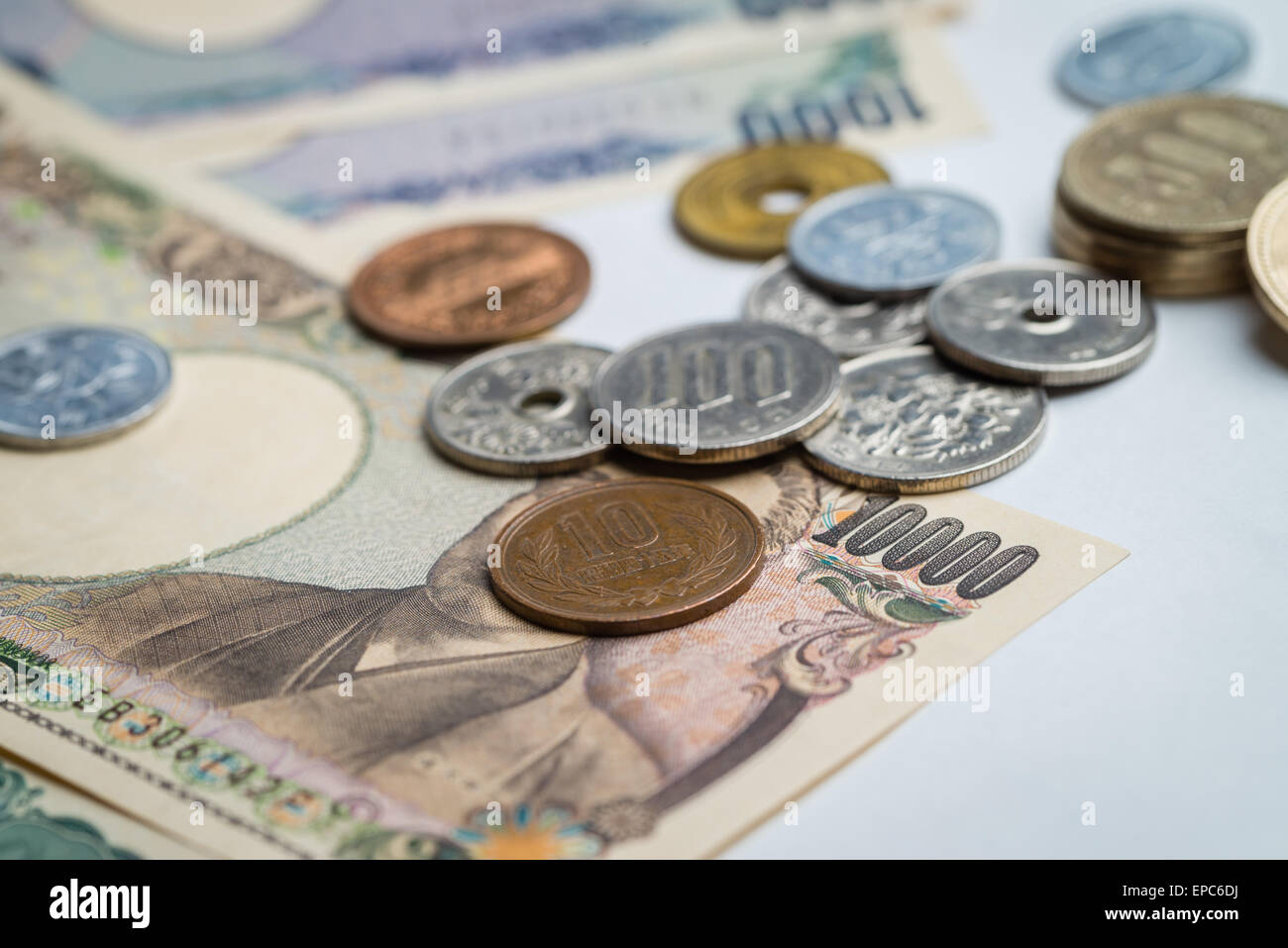 Some Japanese yen bills and coins spread out on a white table Stock ...