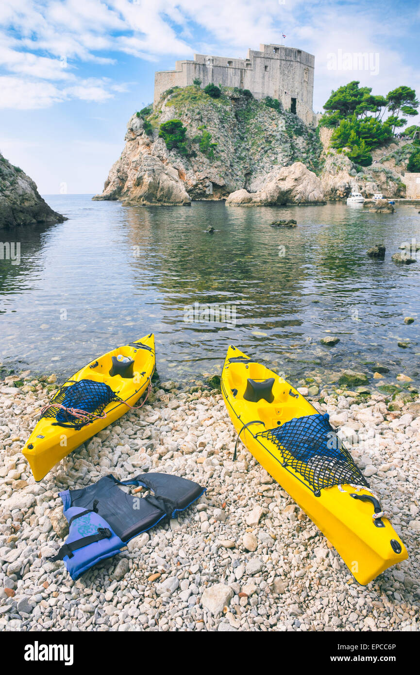 Sea kayaks resting on the rocky shore of a beach near the Old City in ...