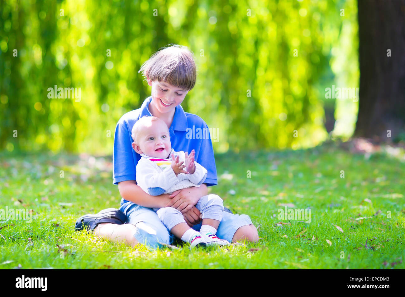 Two brothers, happy school age boy and a little baby, playing together ...
