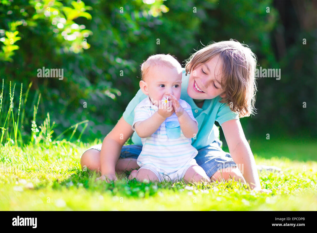 Two brothers, happy school age boy and a little baby, playing together ...