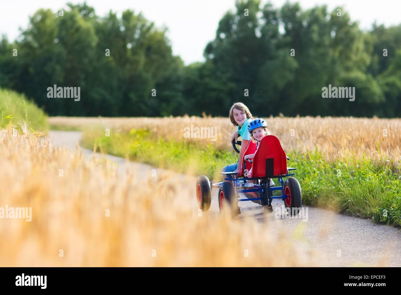 Two happy children playing together enjoying a go cart car ride on a ...