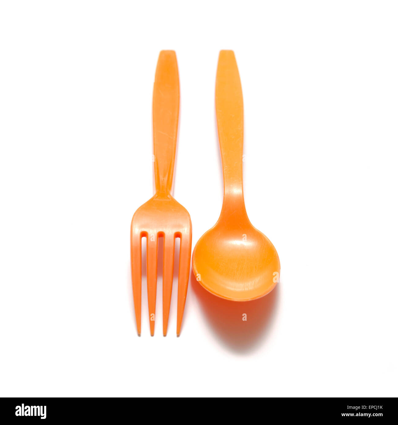 orange plastic spoon and fork on a white background Stock Photo - Alamy