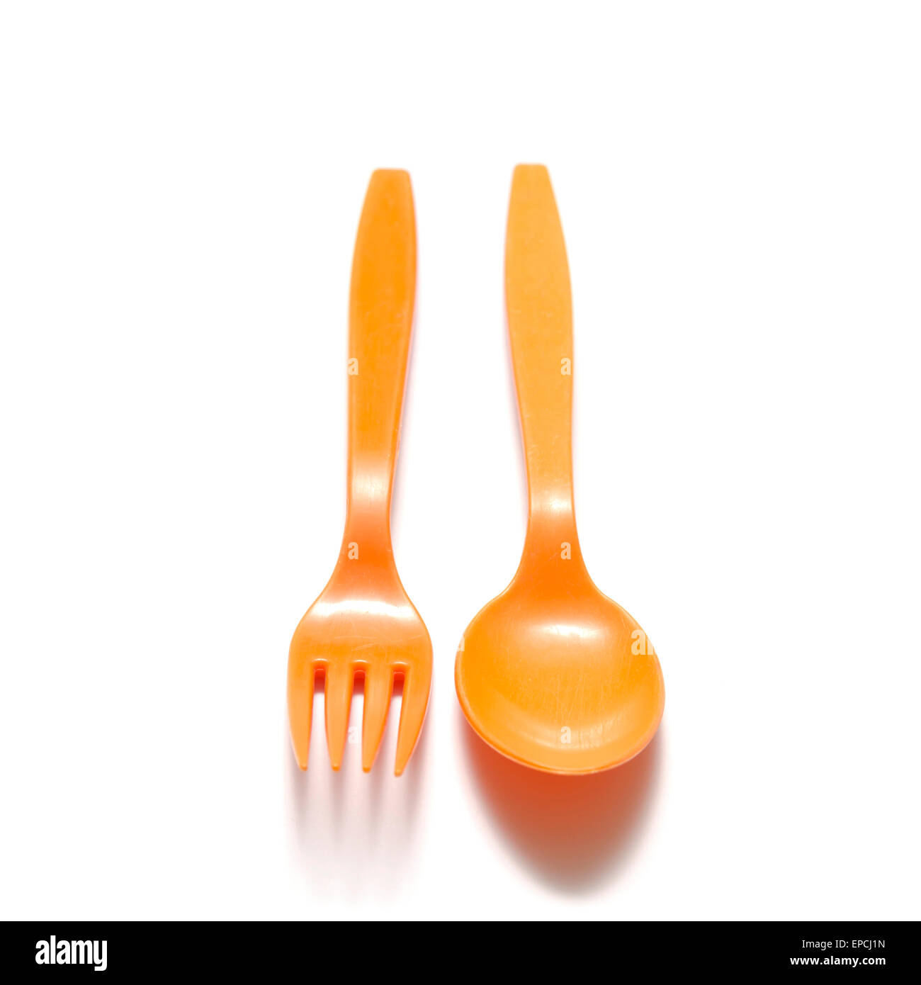 orange plastic spoon and fork on a white background Stock Photo - Alamy