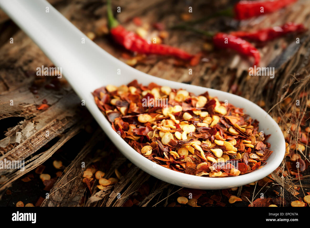 Crushed Chilli Spice in a white spoon on wood Stock Photo - Alamy