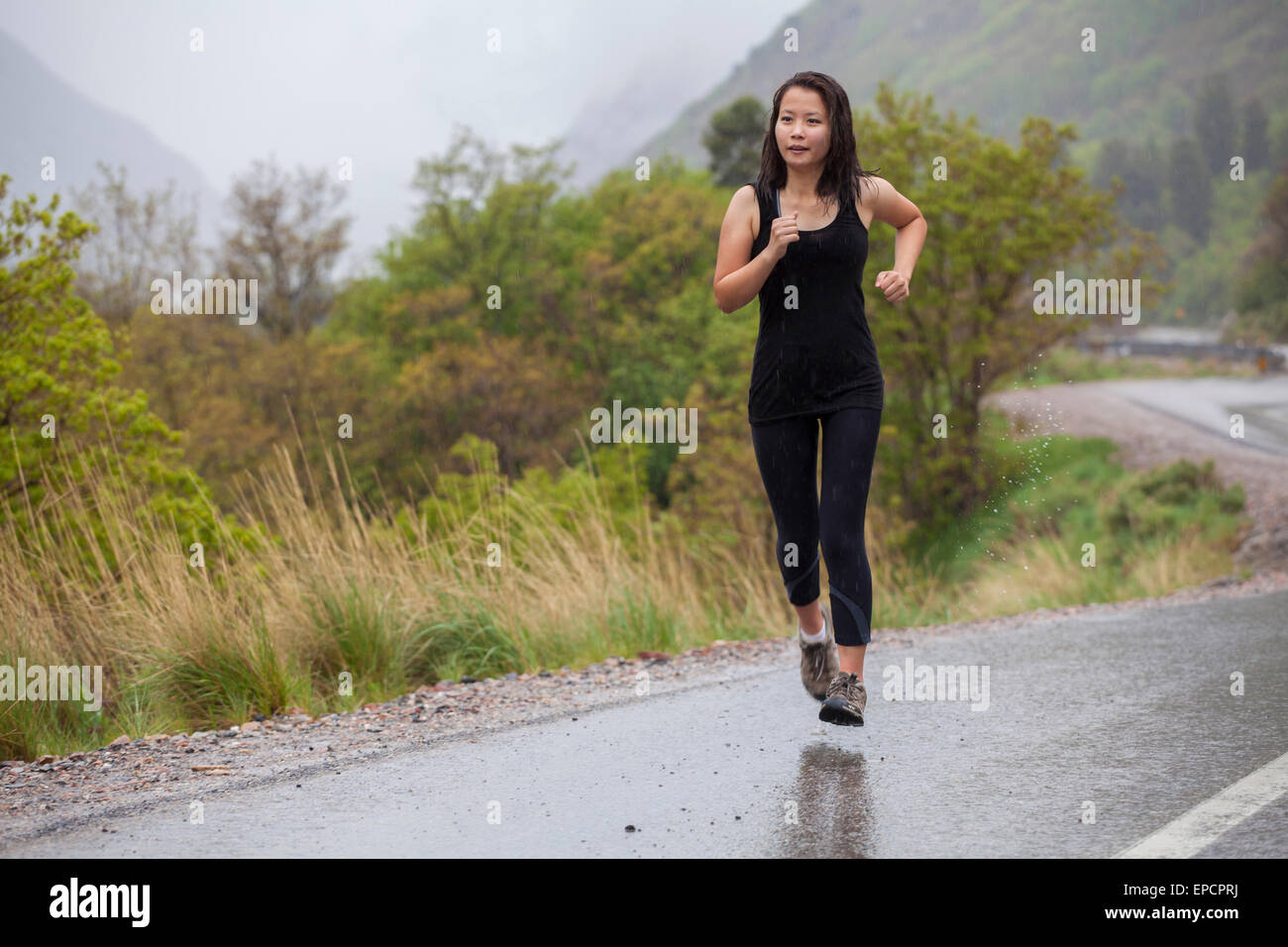 asian woman running in the rain on road in mountains Stock Photo - Alamy