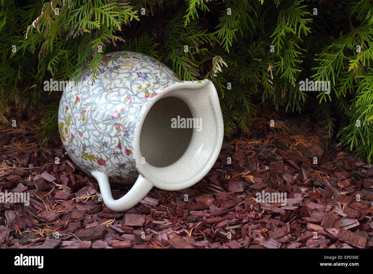 The antique jug with a pattern of flowers lies on brown chipped wood ...