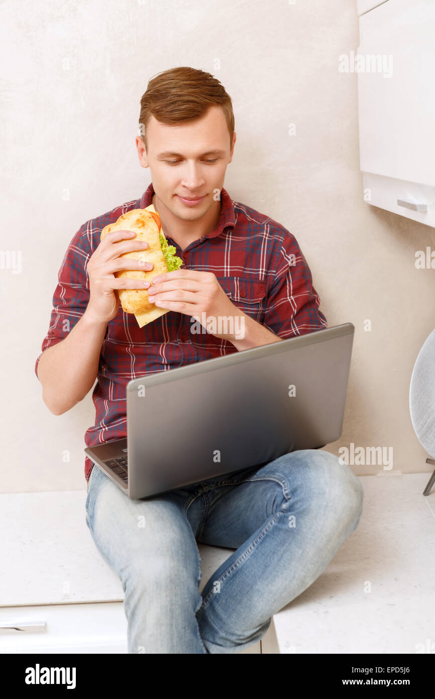 Man holding sandwich and looking at computer screen Stock Photo - Alamy
