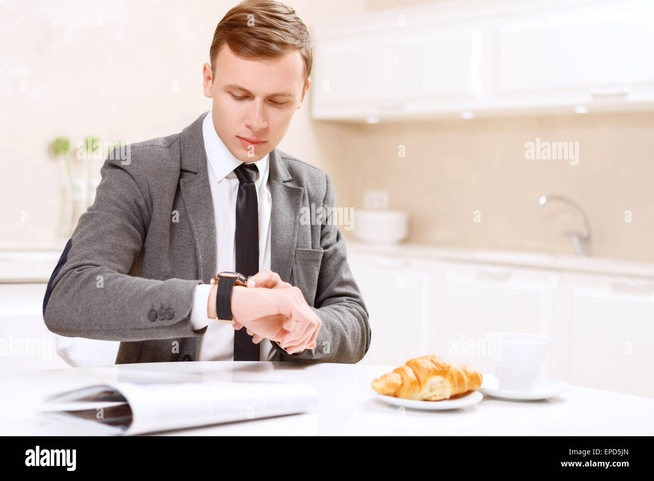 Man looking at his watch in kitchen Stock Photo - Alamy