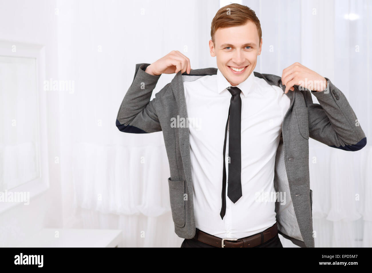 Smiling man putting on jacket Stock Photo - Alamy