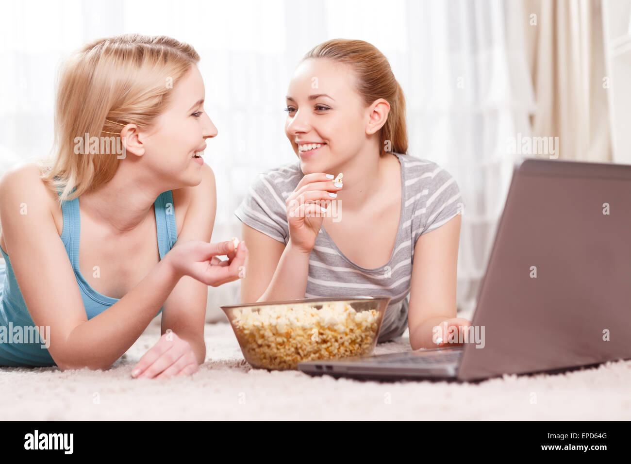 Two young girls eating popcorn Stock Photo - Alamy