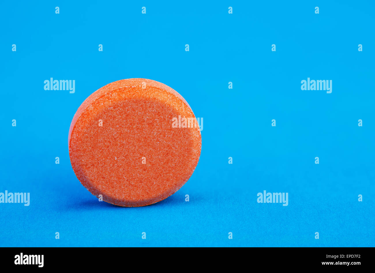 single orange tablet on a blue background Stock Photo - Alamy