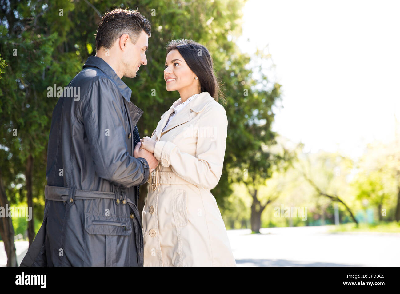 Smiling beautiful couple flirting in park Stock Photo - Alamy
