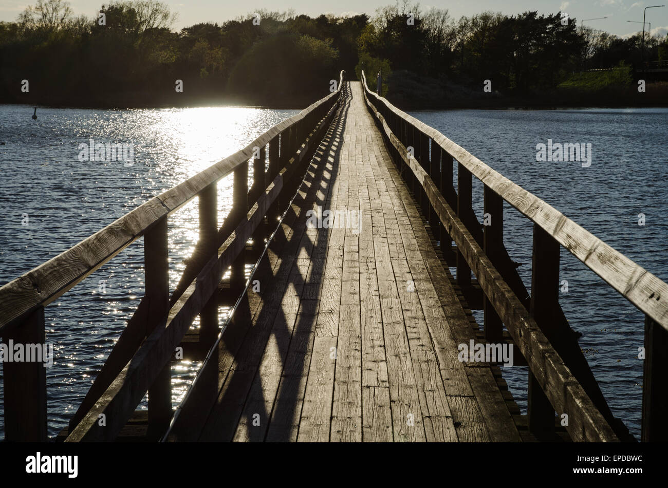 Backlit old wooden footbridge over blue water Stock Photo - Alamy