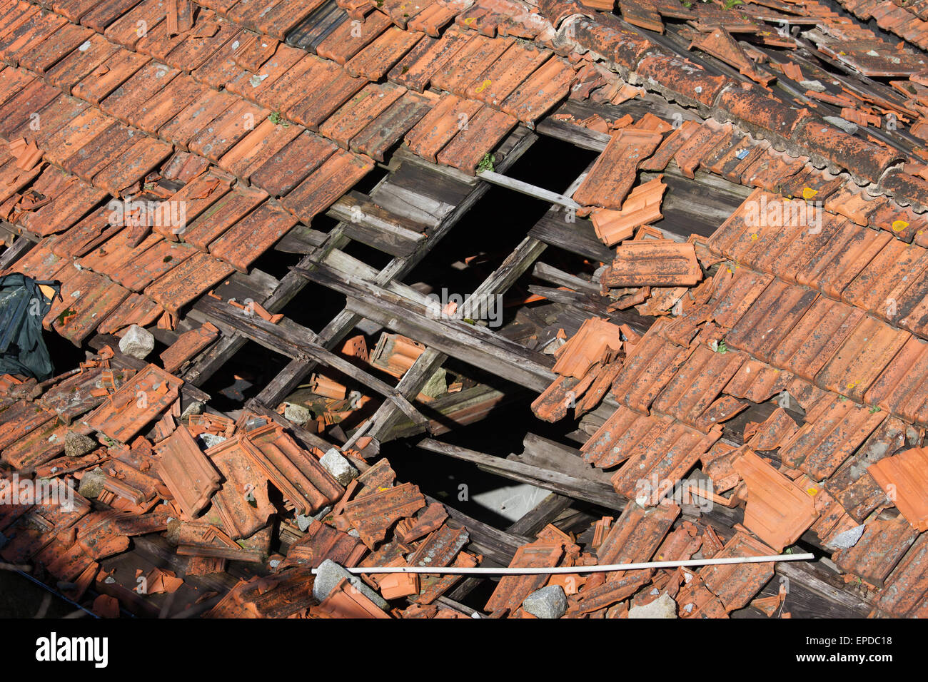 Hole in damaged clay tiled roof with wooden frame of a traditional ...