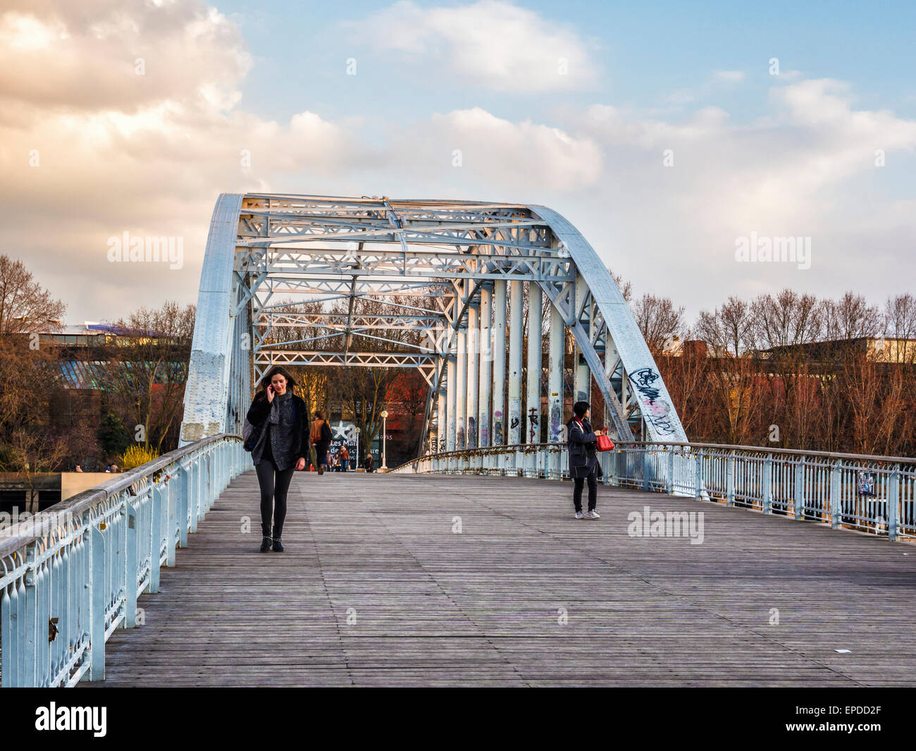 People walk across the Paris Passerelle Debilly iron arched footbridge ...