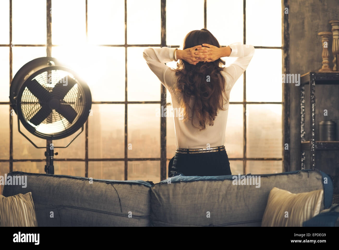 Elegant brunette woman seen from behind, leaning against the back of a ...