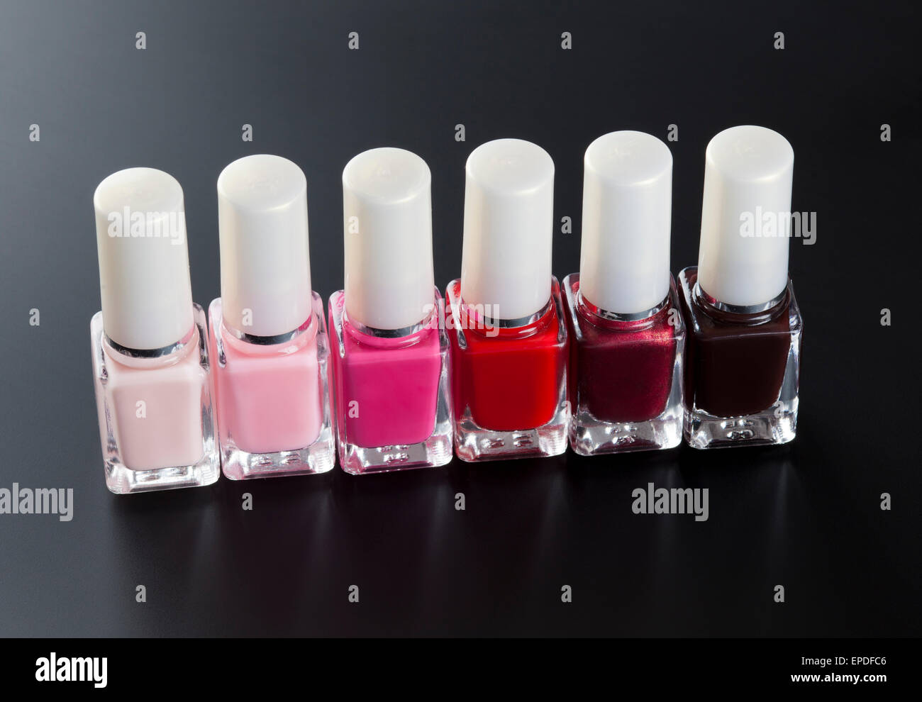 Nail polishes in a row on black background Stock Photo - Alamy