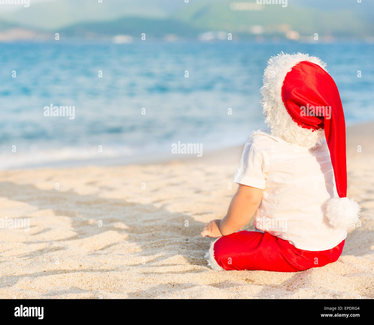 Little Santa boy on the beach Stock Photo - Alamy