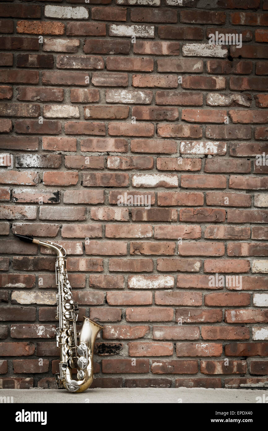 Lone old saxophone leans against brick wall outside abandoned jazz club ...