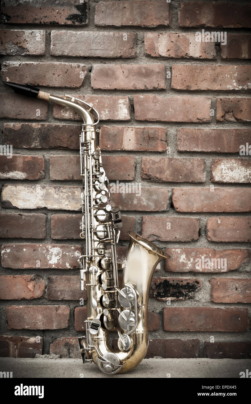Lone old saxophone leans against brick wall outside abandoned jazz club ...