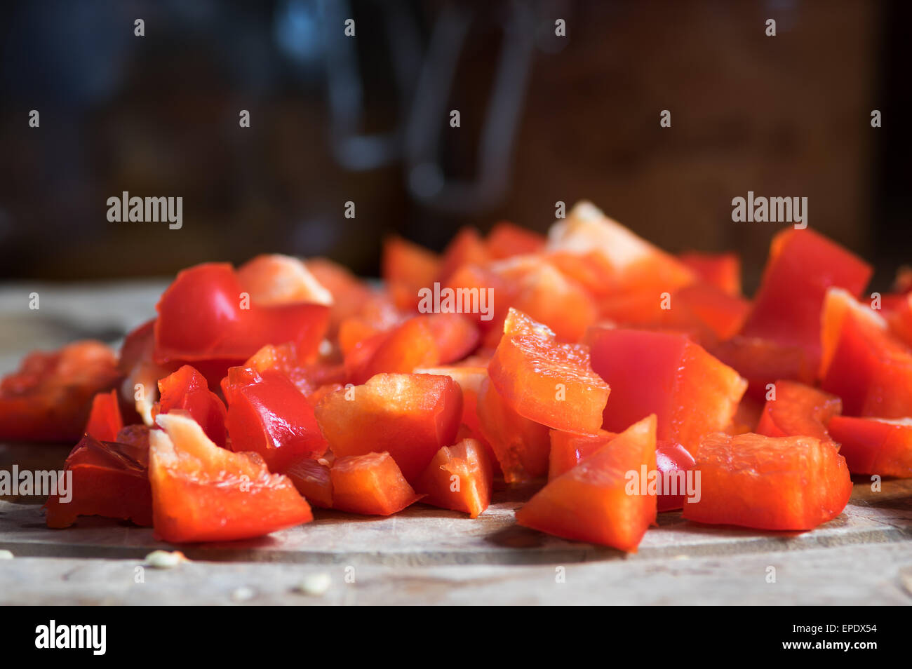 A red pepper, chopped up ready to be cooked with, on a rustic chopping ...
