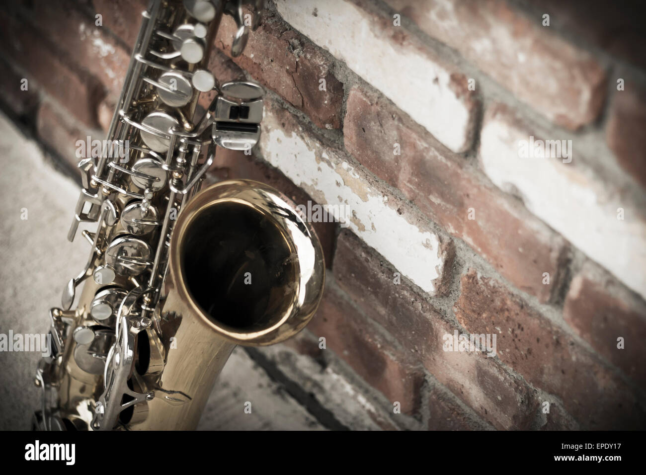Lone old saxophone leans against brick wall outside abandoned jazz club ...