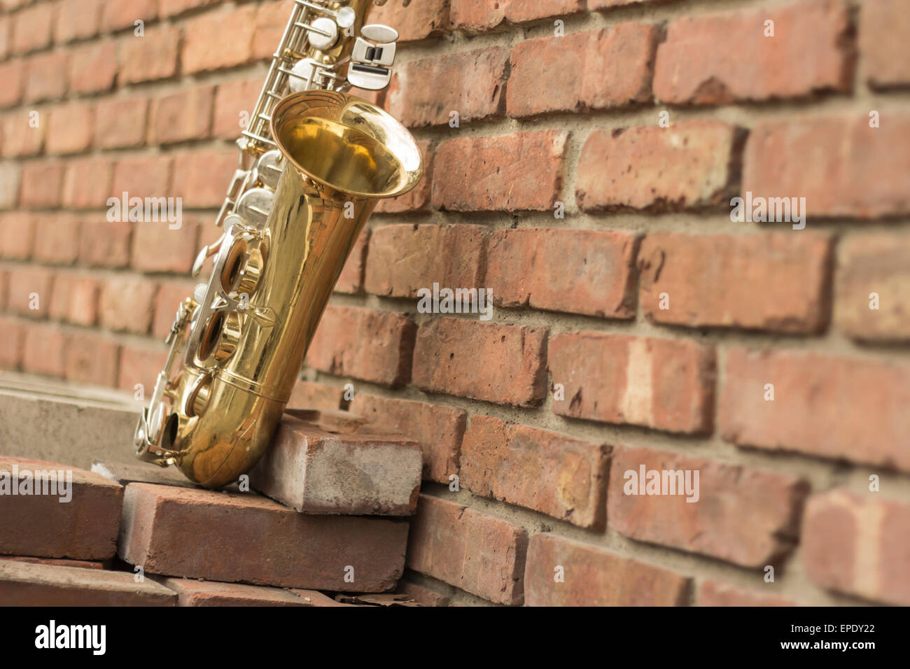 Lone old saxophone leans against brick wall outside abandoned jazz club ...