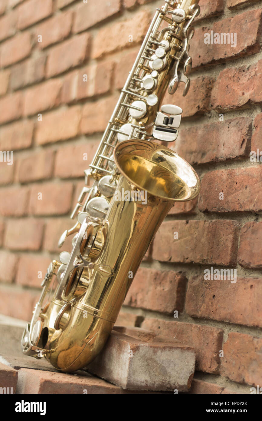 Lone old saxophone leans against brick wall outside abandoned jazz club ...