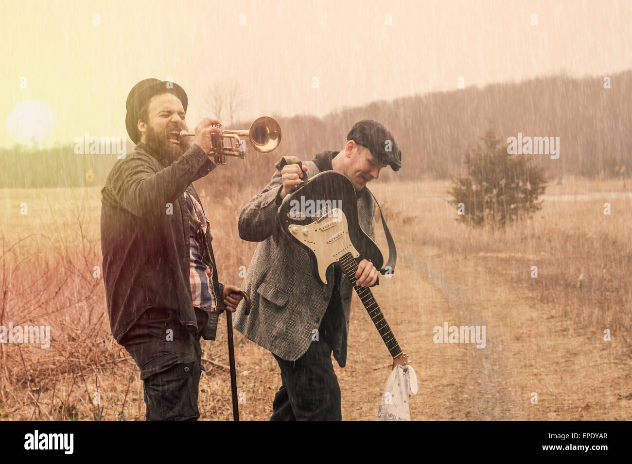 Stylish gypsies play trumpet and electric guitar on a wilderness path ...
