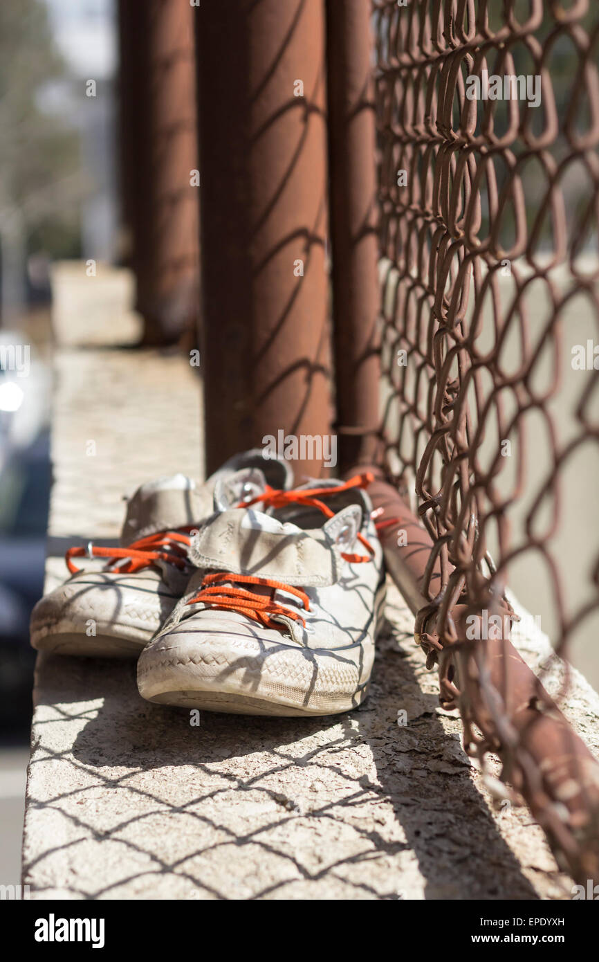 Pair of old worn classic sneakers hang from rusty chain link fence ...