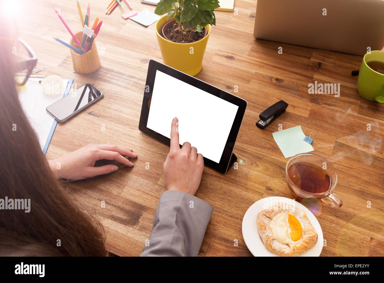 Young woman working with tablet placed on wooden desk with blank screen ...