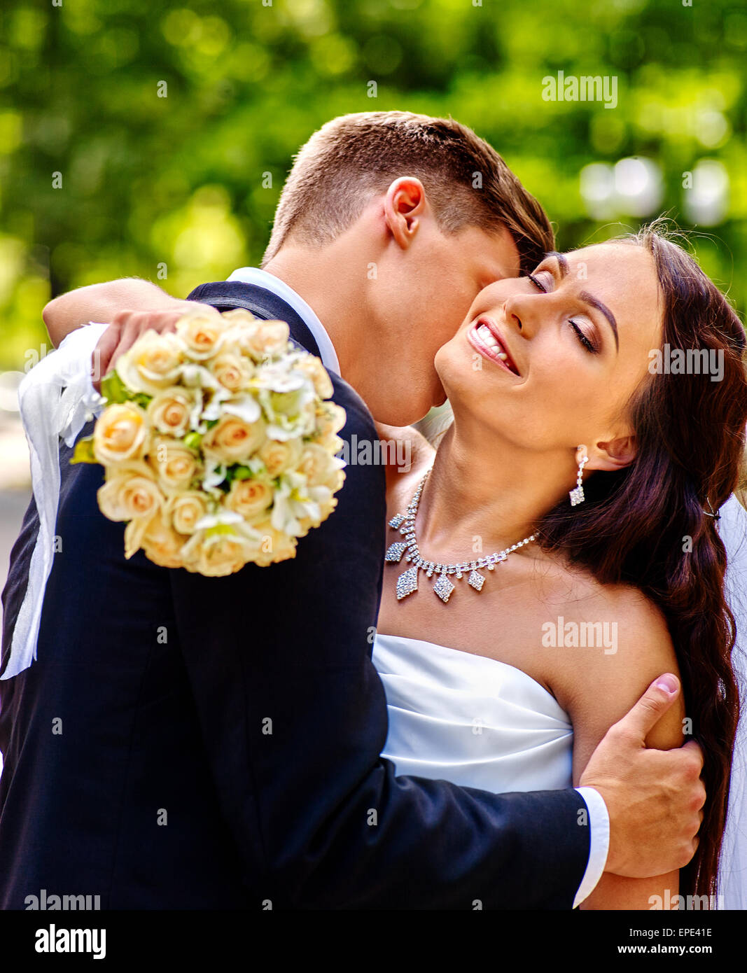 Groom kissing bride on shoulder Stock Photo - Alamy