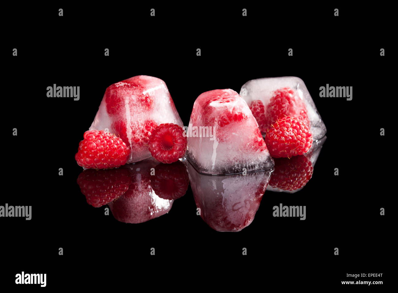 Delicious raspberries frozen in ice cubes isolated on black background ...