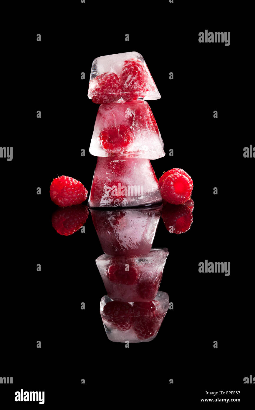 Raspberries frozen in ice cubes isolated on black background. Healthy ...