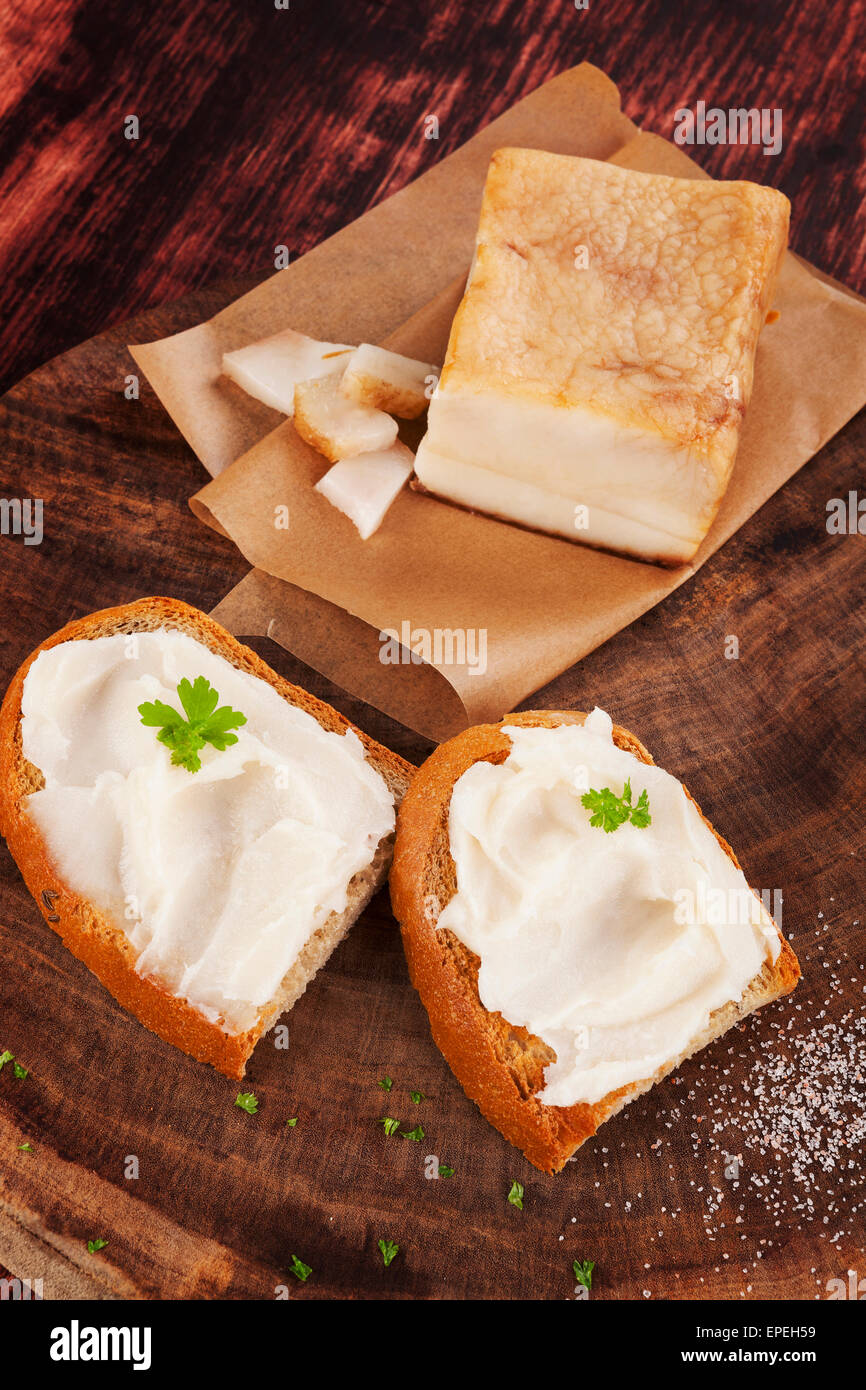 Bread slice with lard on vintage wooden chopping board on wooden ...