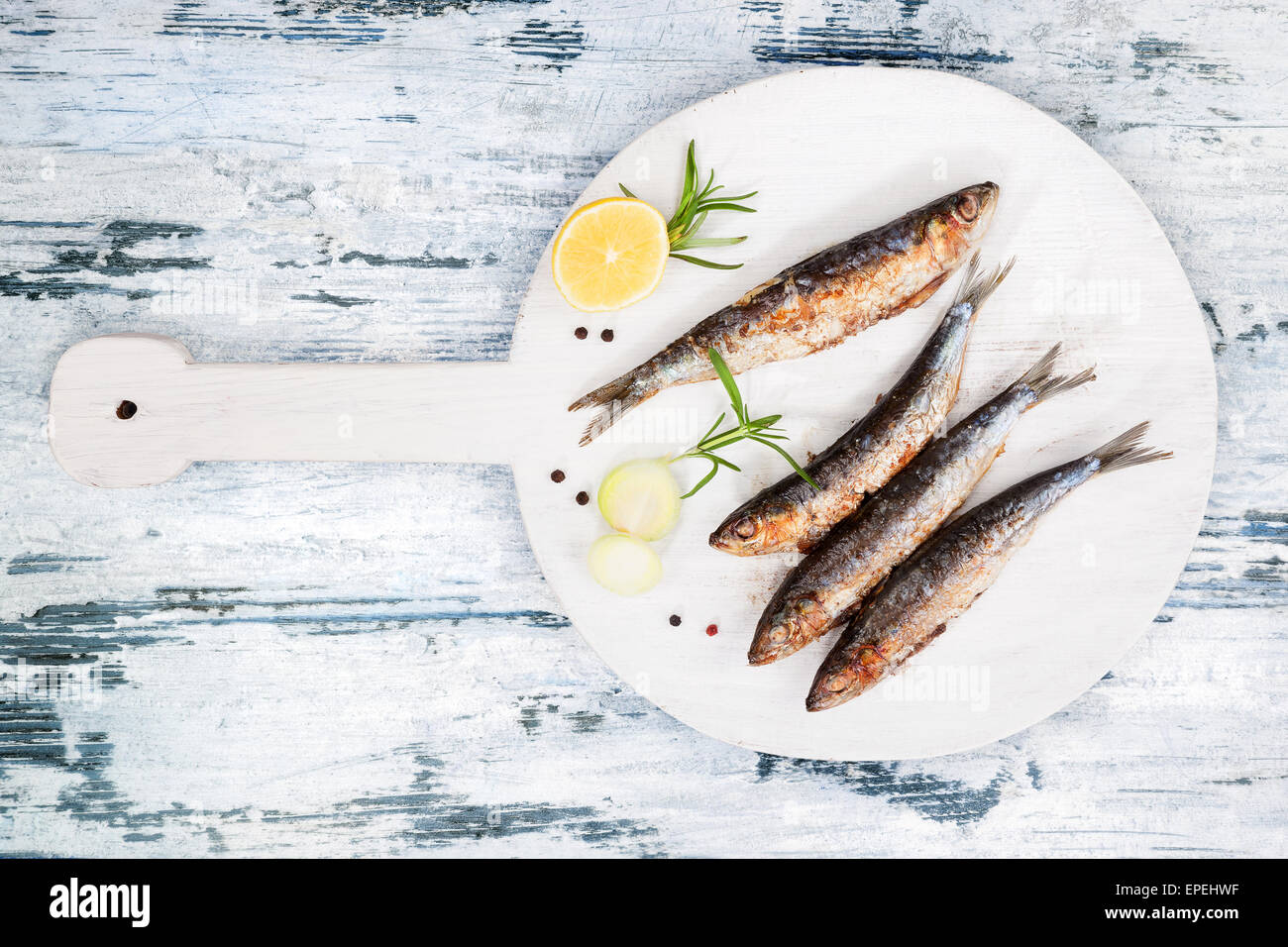 Delicious grilled sardines on wooden kitchen board on white and blue ...