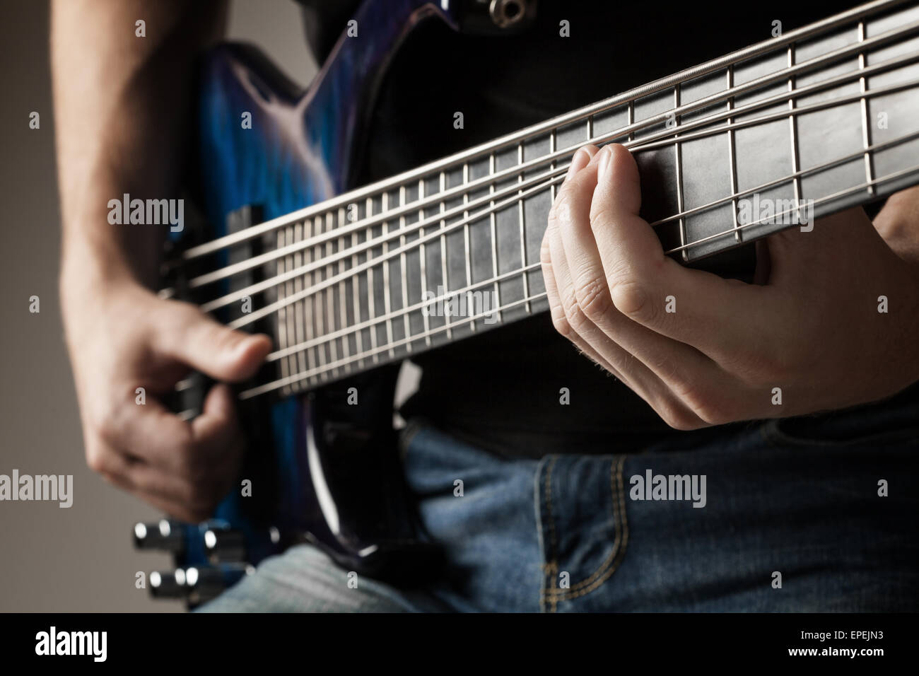 male musician playing on six-string bass guitar Stock Photo - Alamy