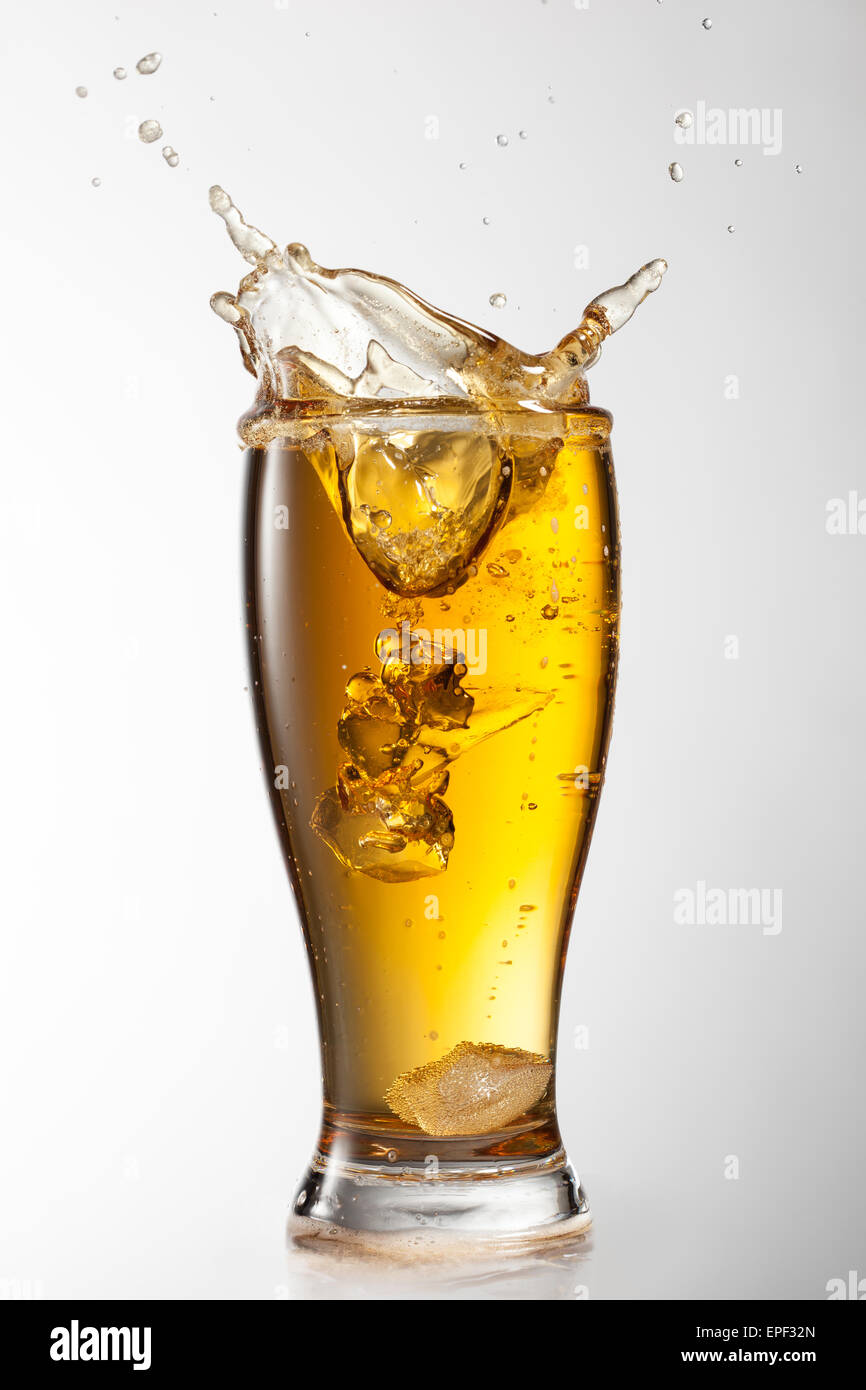 Ice falling into beer glass with splash isolated Stock Photo - Alamy