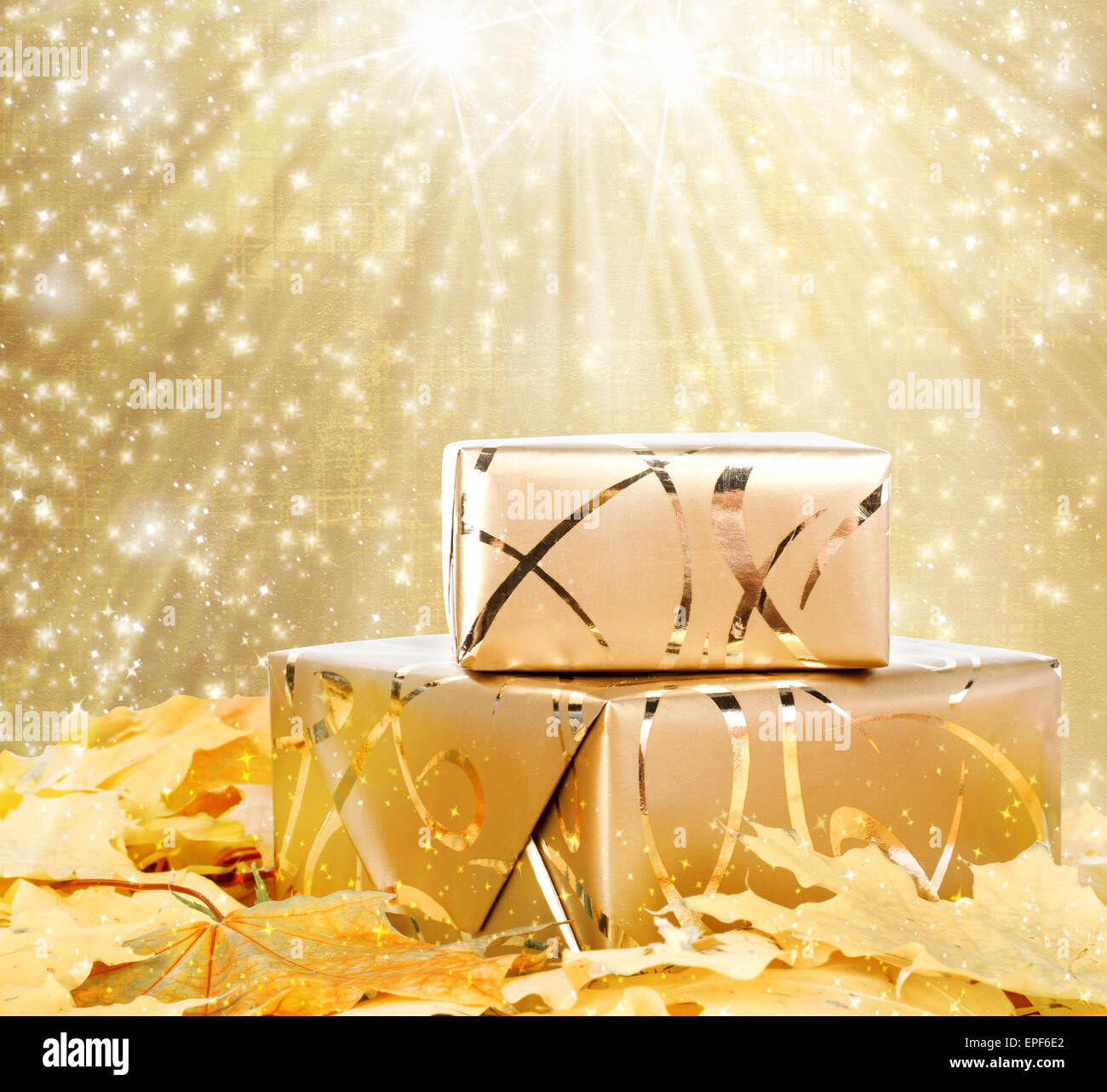 Gift box in gold wrapping paper with autumn leaves on the abstract ...