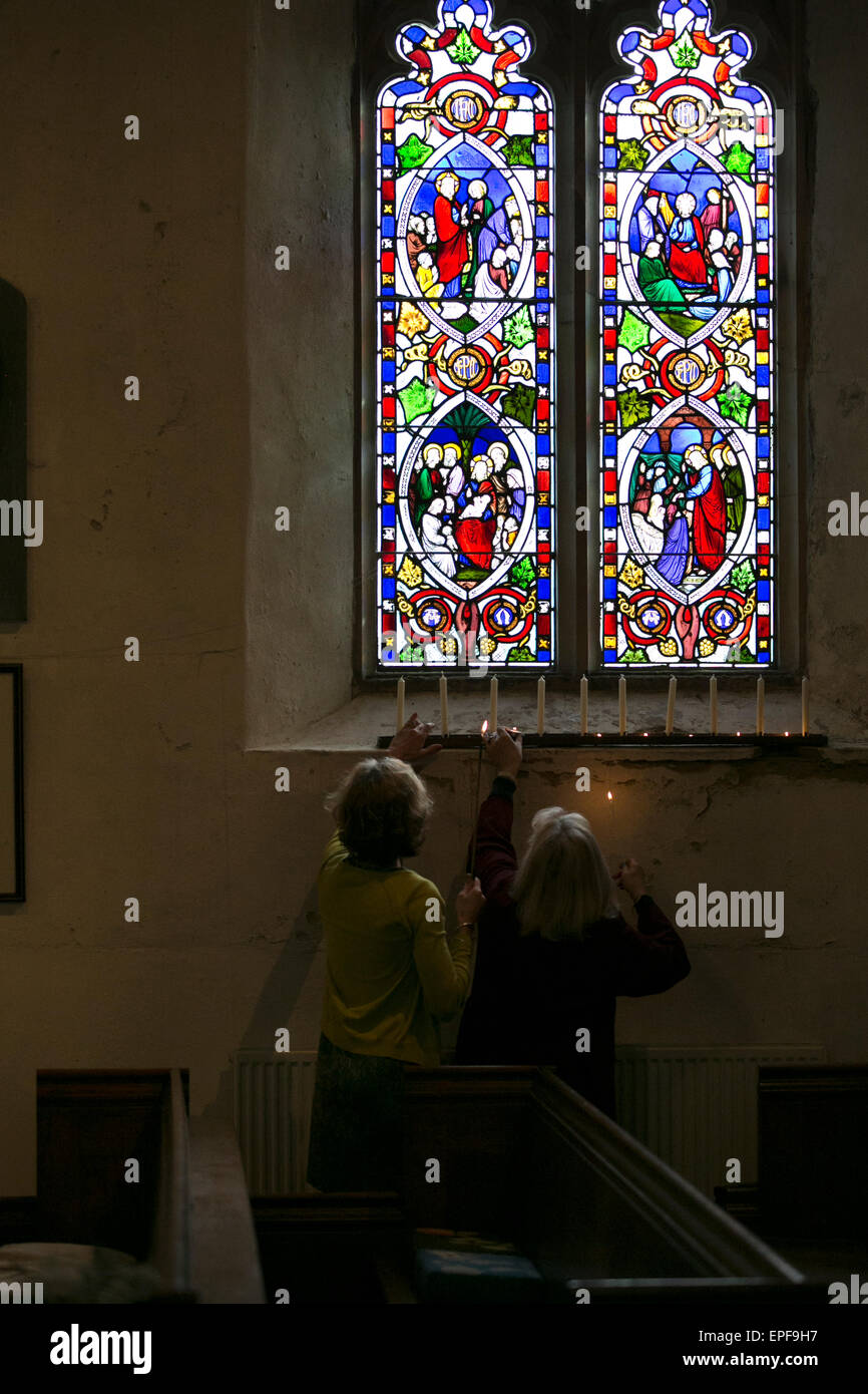 women lighting candles below stained glass window in a church Stock ...