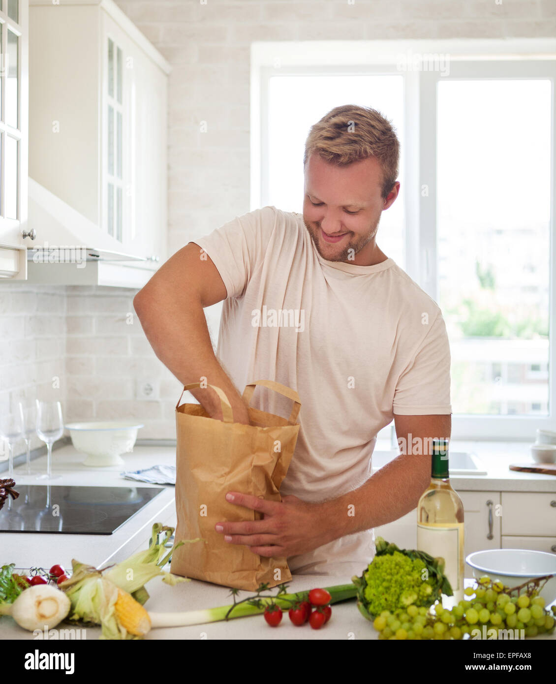 Man holding paper bag full of groceries on the kitchen Stock Photo - Alamy