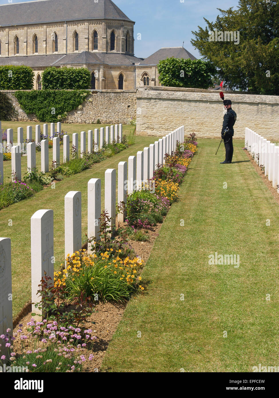 A lone male soldier stands beside Allied British Cemetary graves from D ...