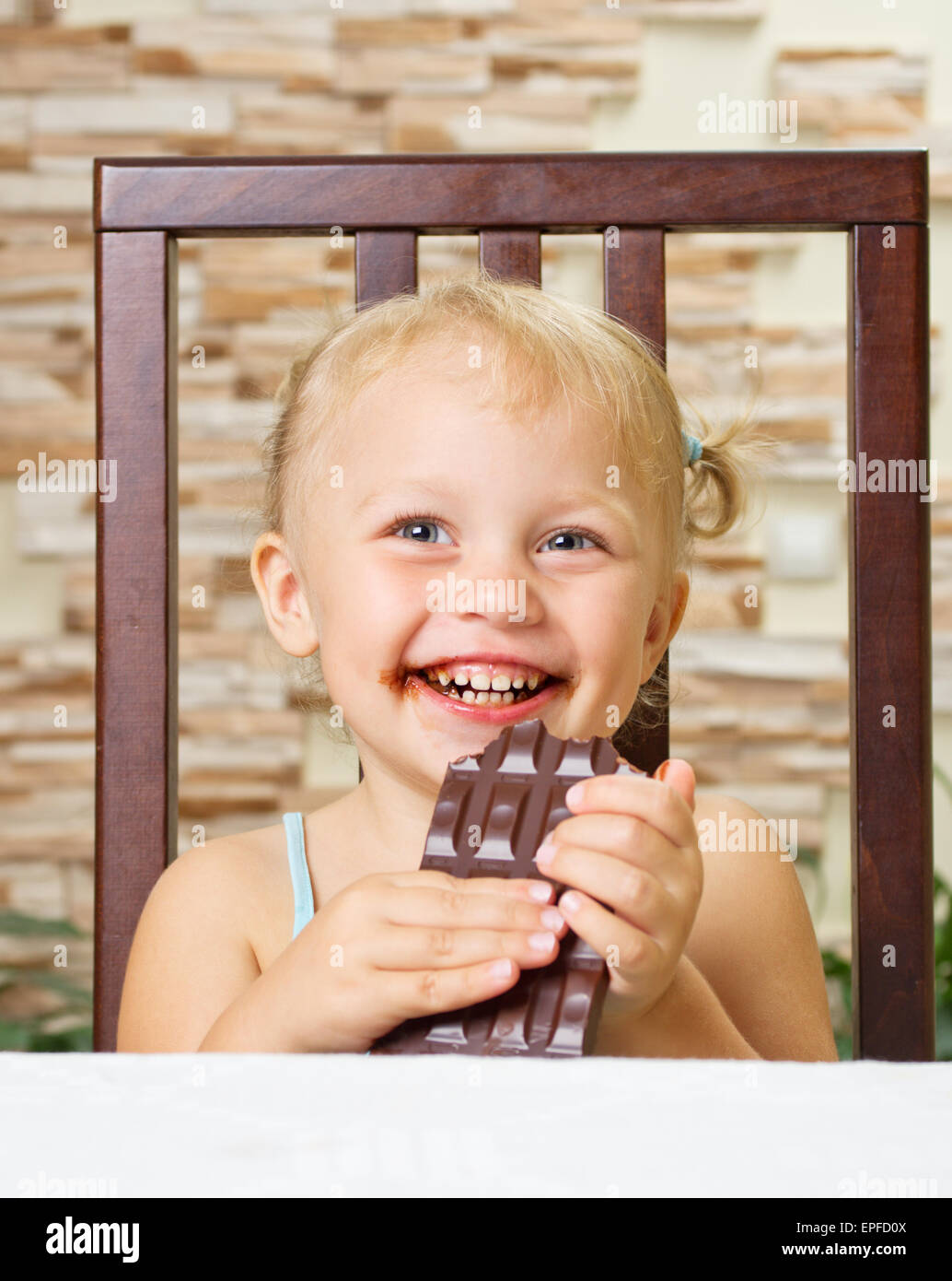 Little smiling girl with chocolate at the table Stock Photo - Alamy